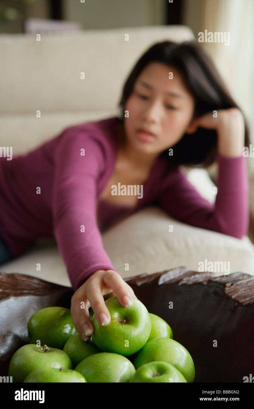 Young woman reaching for apple Stock Photo - Alamy