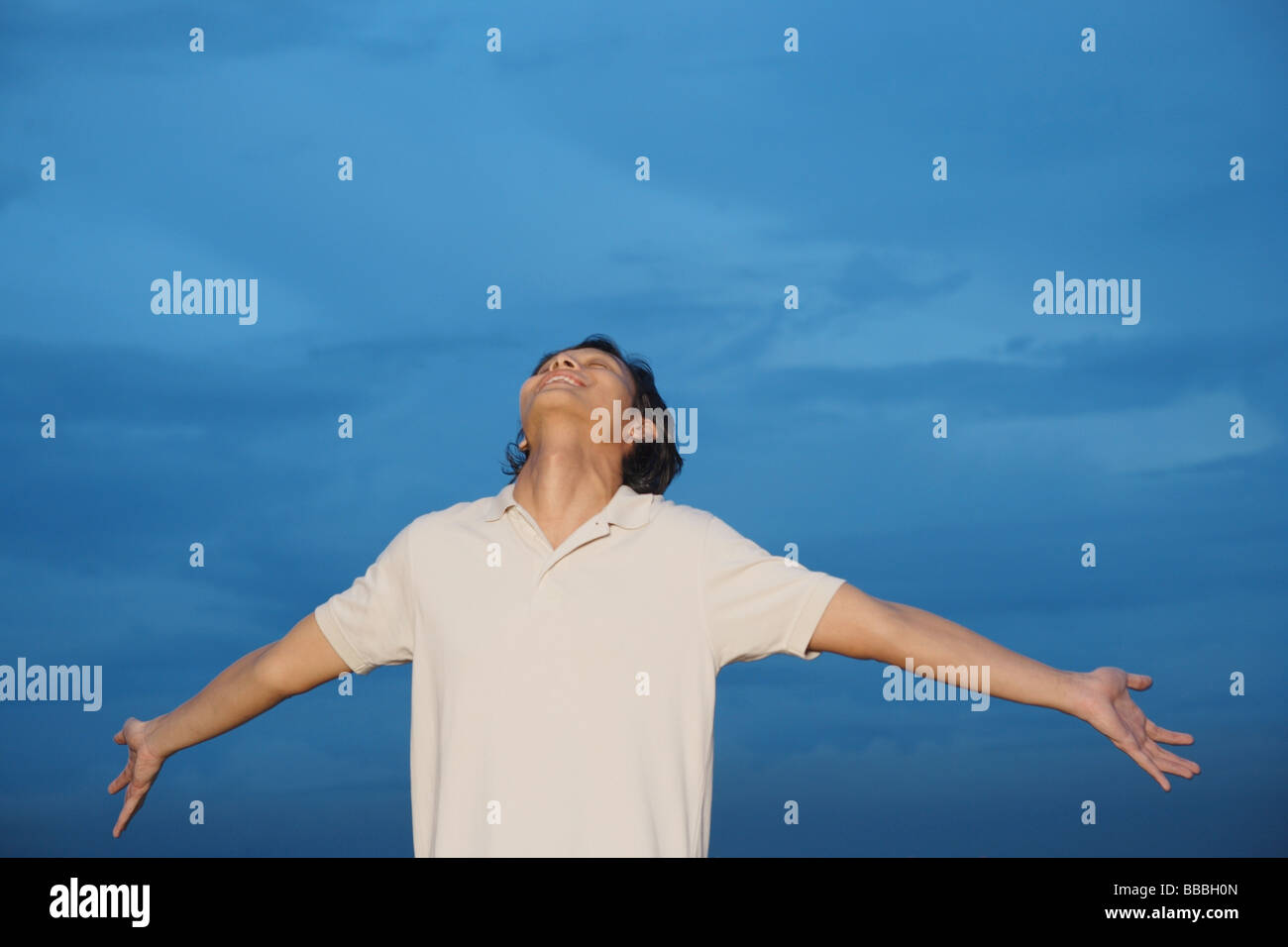 Man standing with arms outstretched, looking up Stock Photo - Alamy