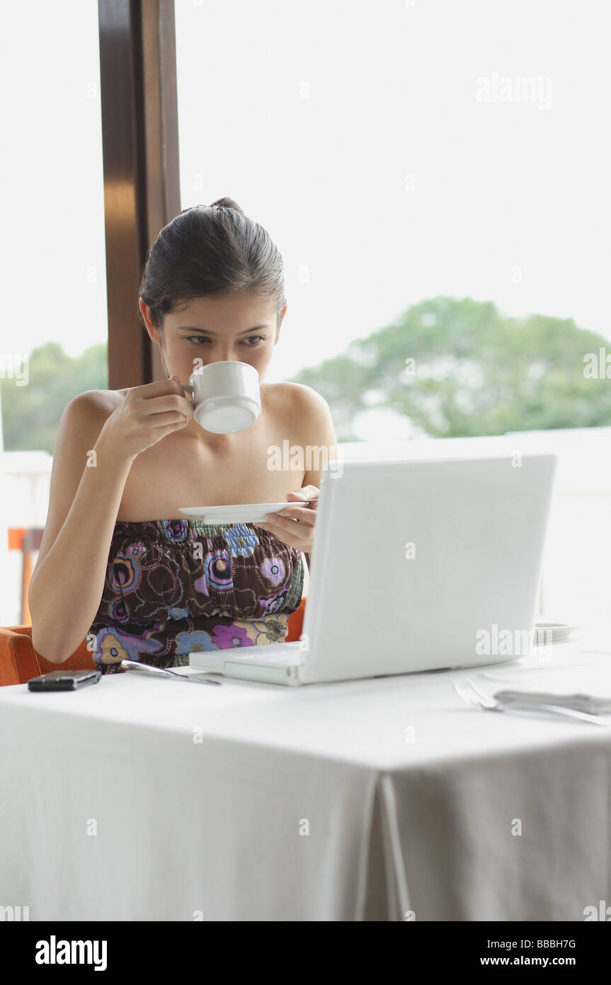Woman sitting in restaurant, using laptop, drinking from cup Stock ...