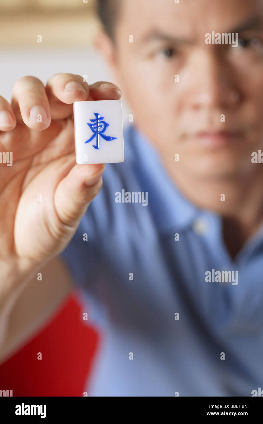 Man holding mahjong tile with Chinese script meaning East Stock Photo ...