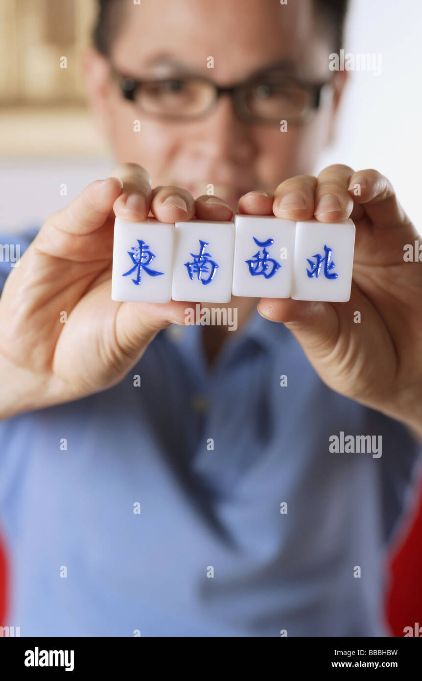 Man holding mahjong tiles with Chinese characters for East, South, West ...