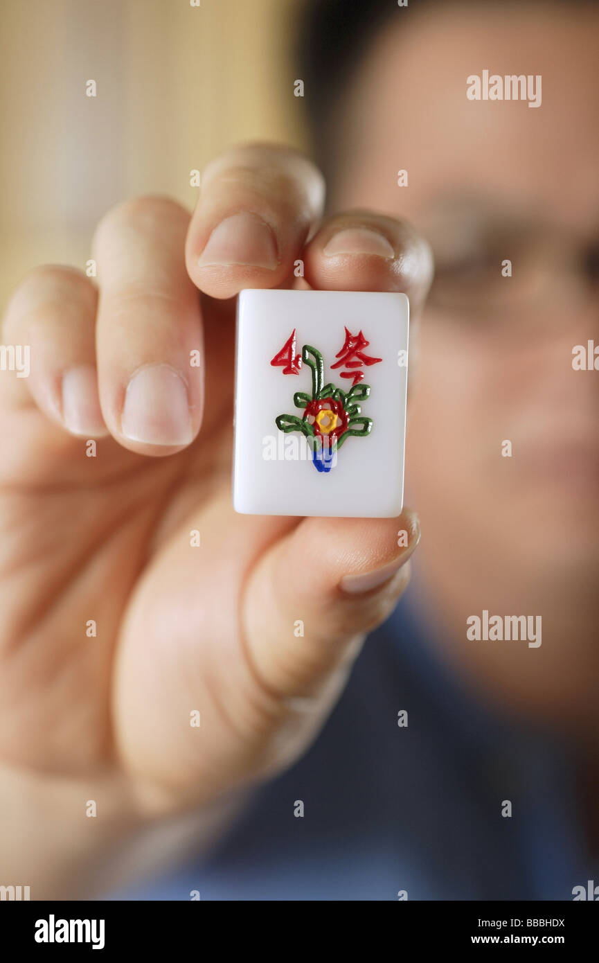 Close-up of hand holding mahjong tile with the Chinese script for ...