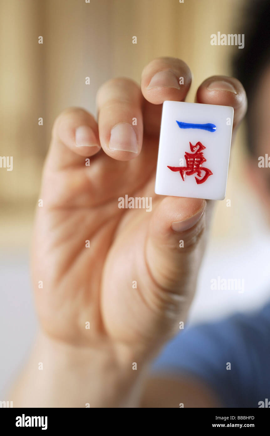 Close-up of hand holding mahjong tile with Chinese script Stock Photo ...