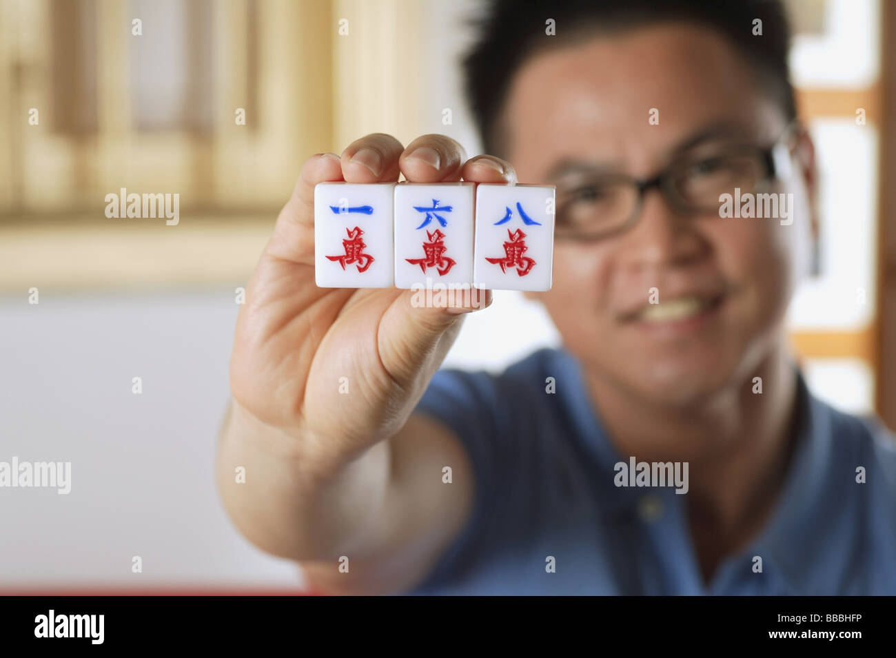 Man holding mahjong tiles with Chinese characters for One, Six and ...