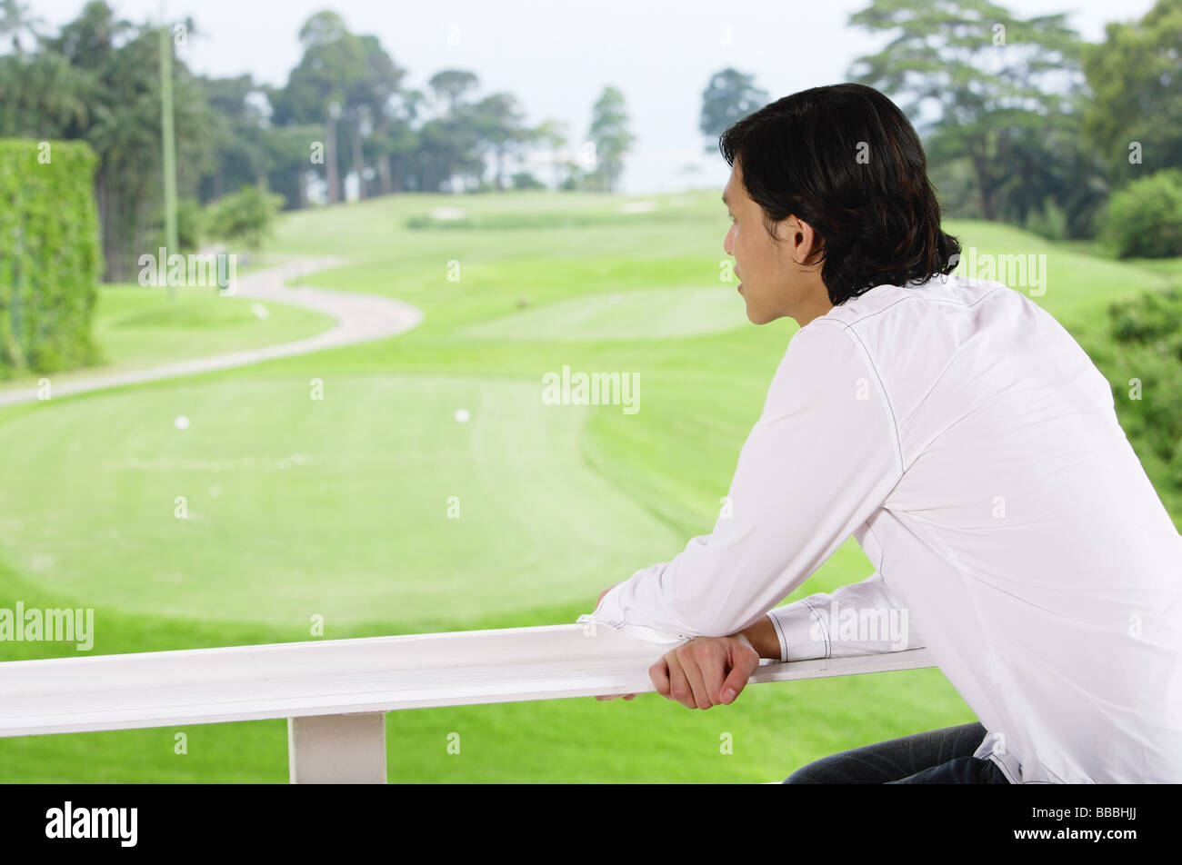 Man leaning on railing, looking out at golf course Stock Photo - Alamy