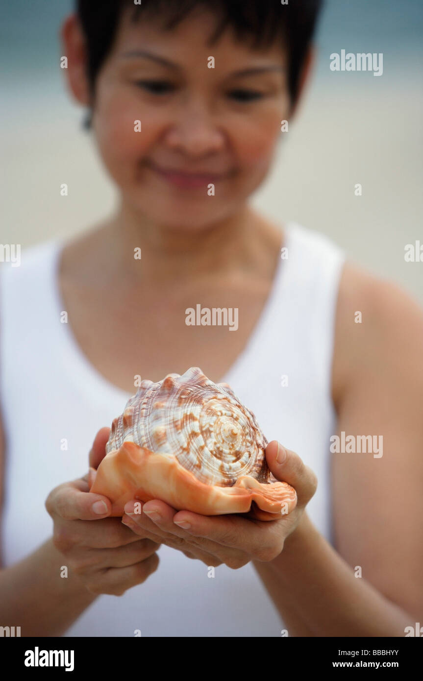 Woman at the beach holding a sea shell Stock Photo - Alamy