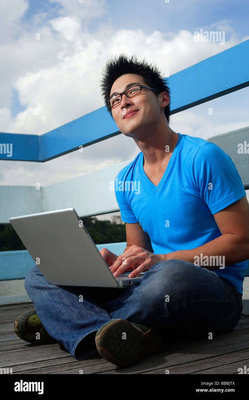 Man sitting with laptop, looking up Stock Photo - Alamy