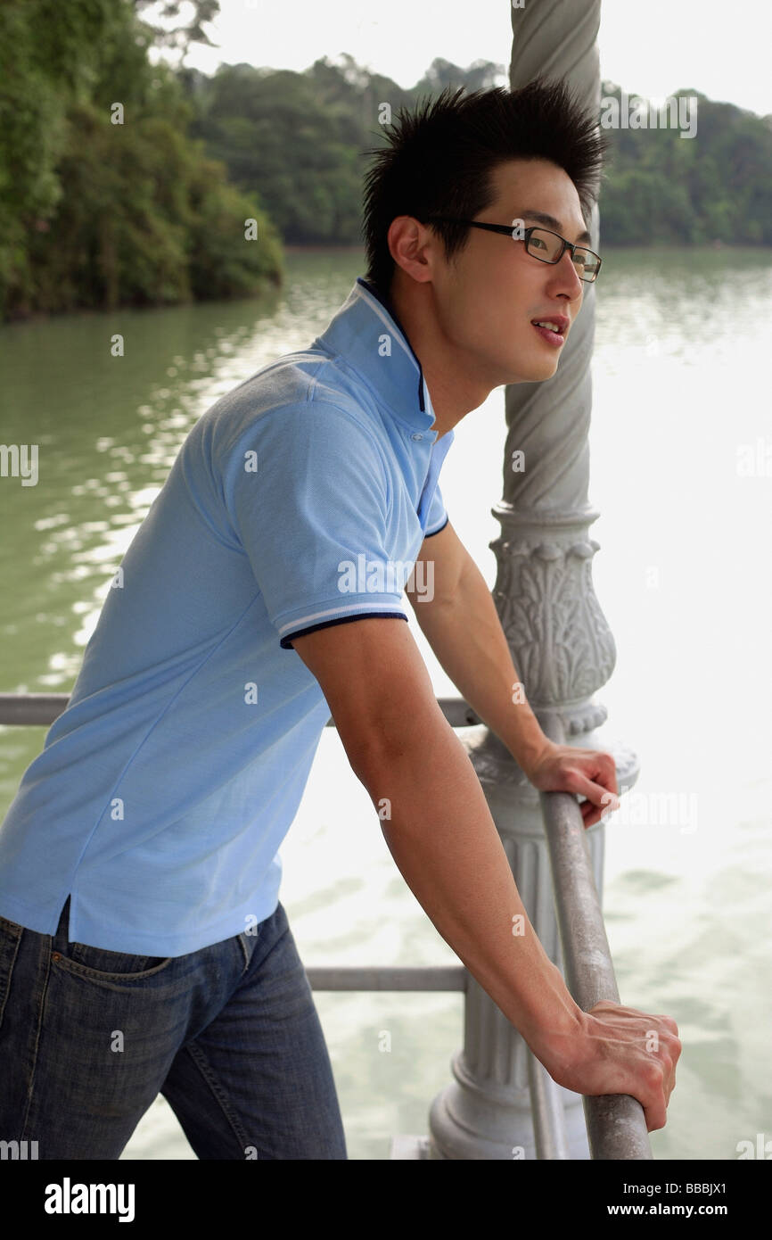 Man leaning on railing, looking out over body of water Stock Photo - Alamy