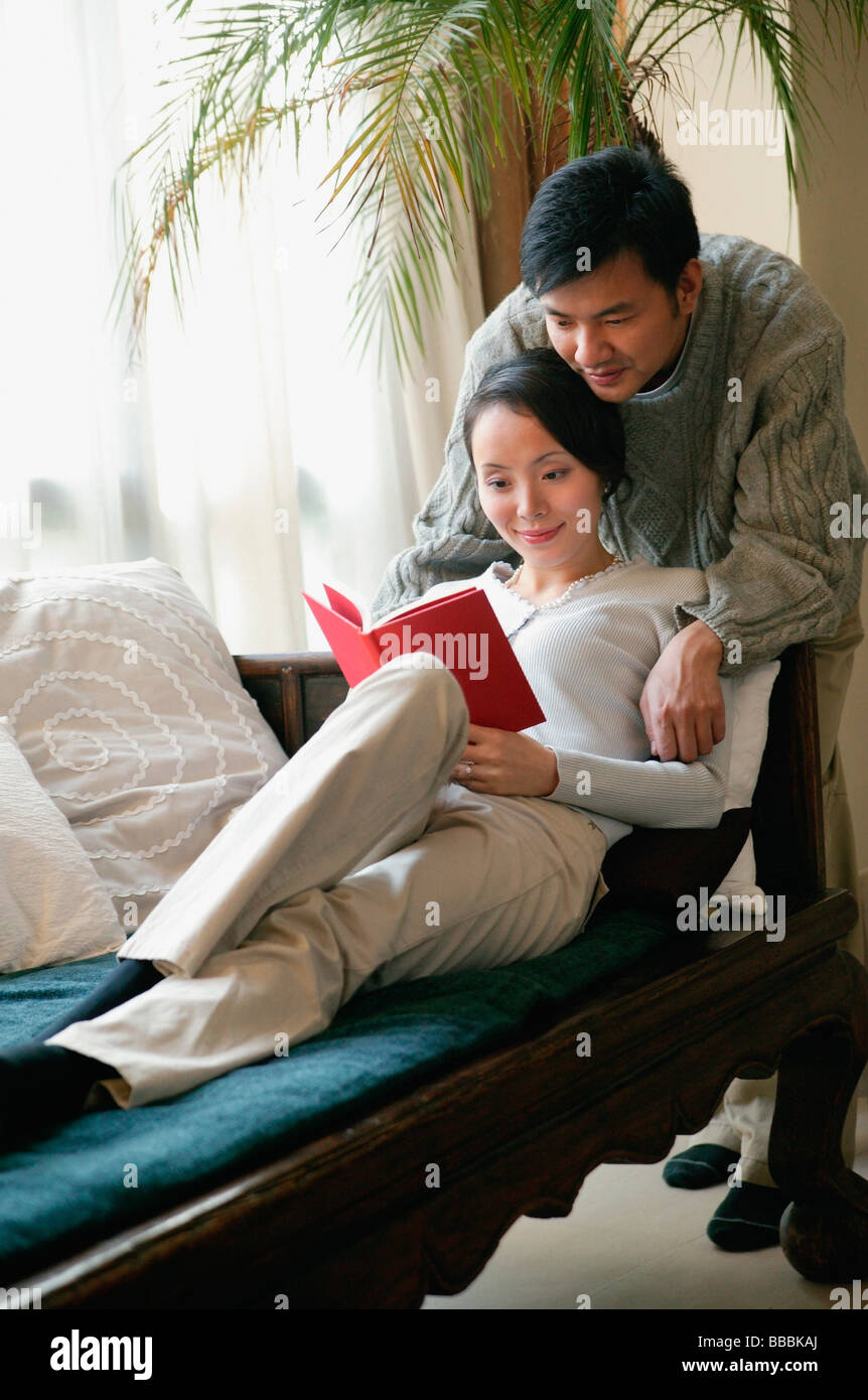 Couple in living room, woman reading a book, man leaning over her Stock ...
