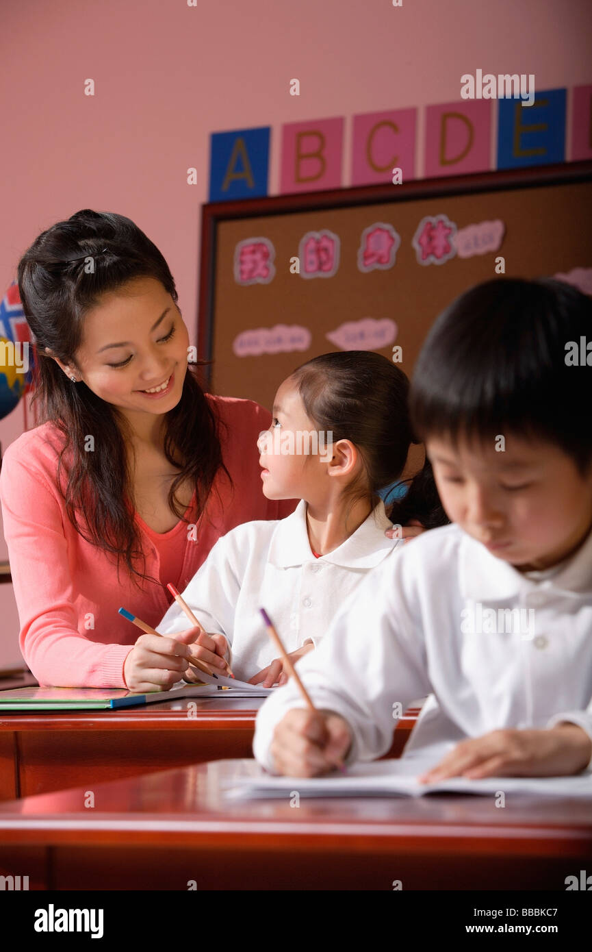 Students in class with teacher looking at schoolgirl Stock Photo - Alamy
