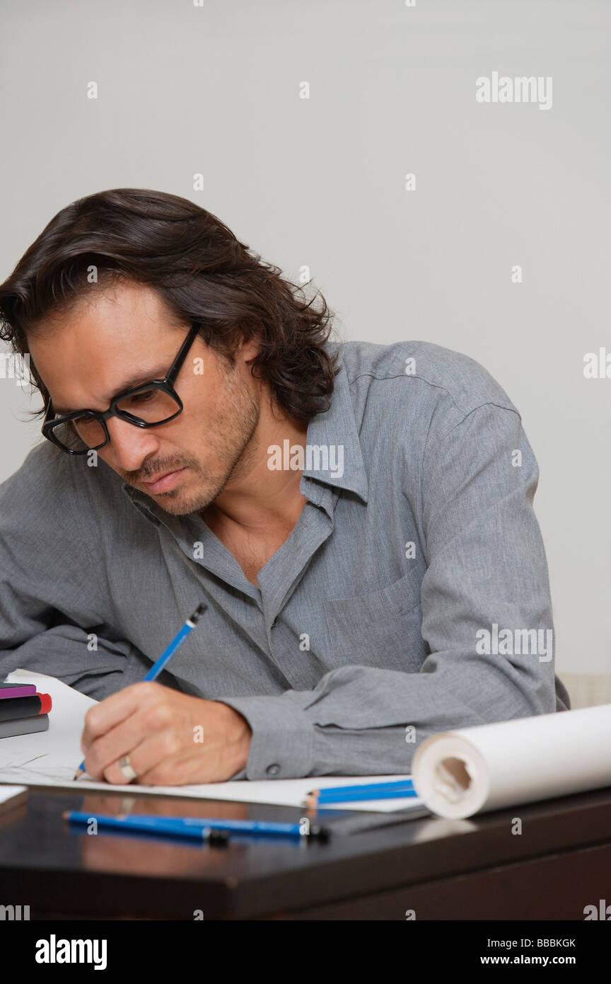 Man sitting at desk drawing Stock Photo - Alamy