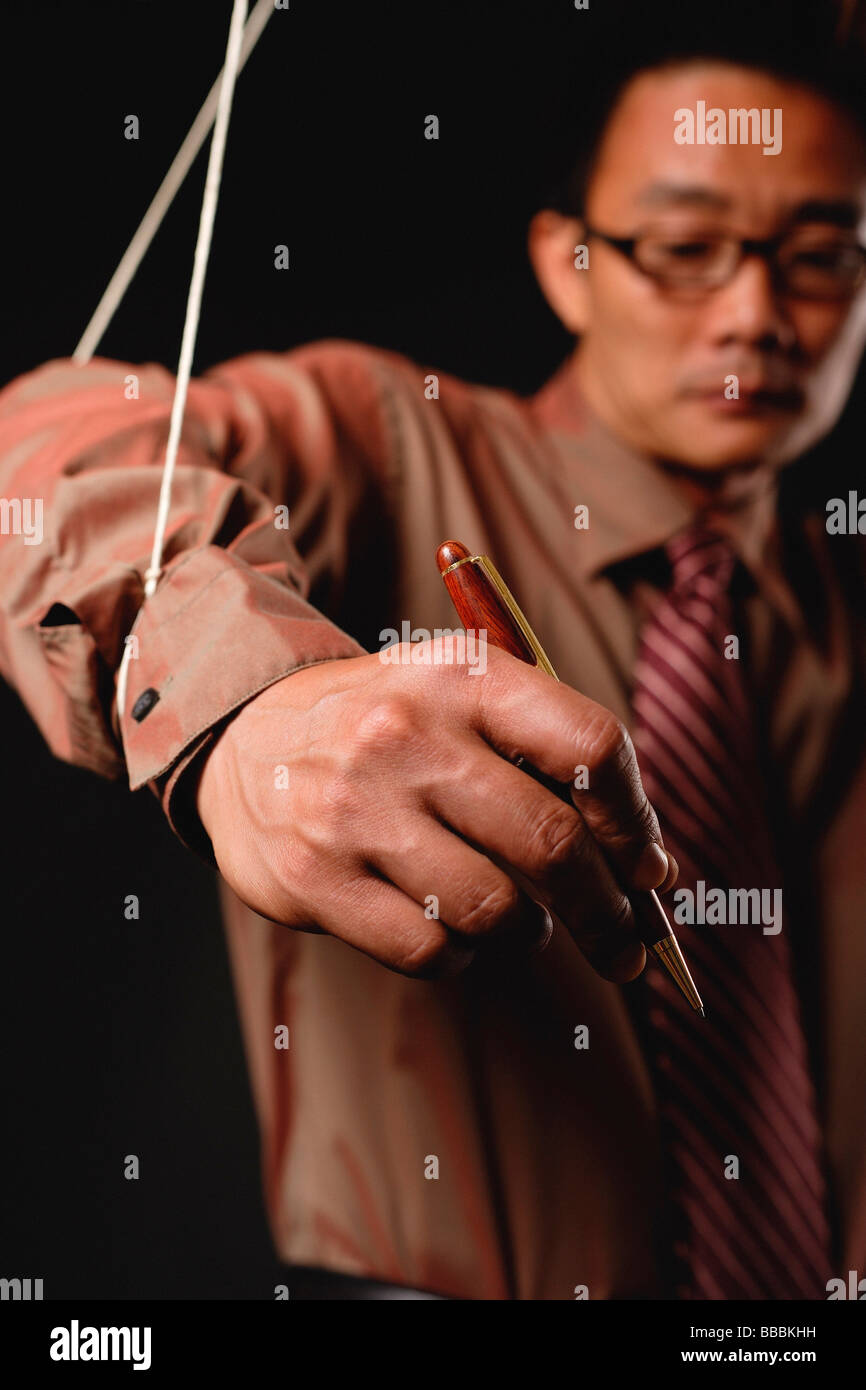 Man with marionette strings attached to his hands, holding pen Stock ...