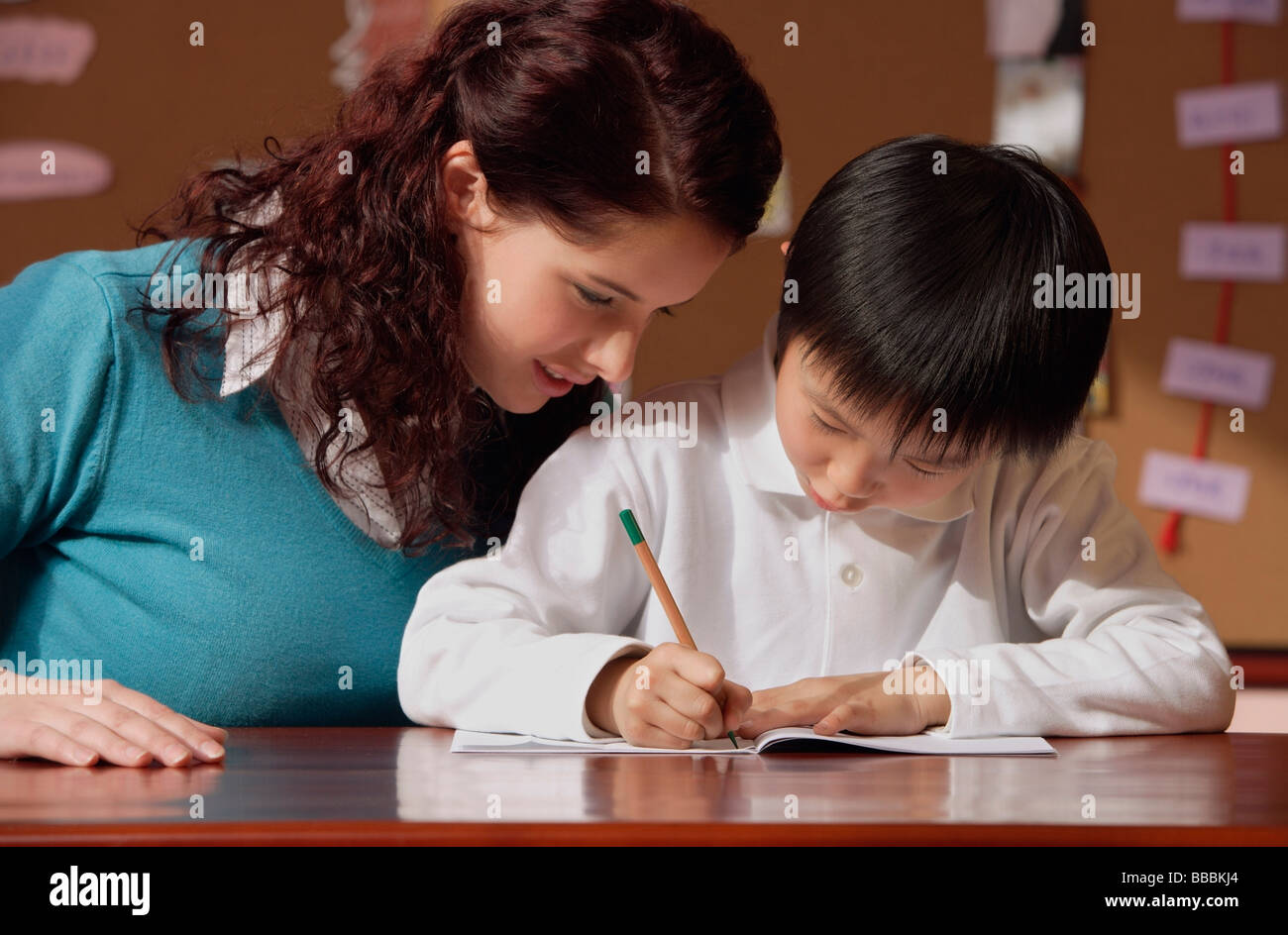 Teacher helping young student Stock Photo - Alamy