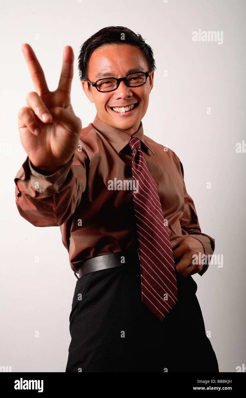 Nerdy businessman making peace hand sign Stock Photo - Alamy