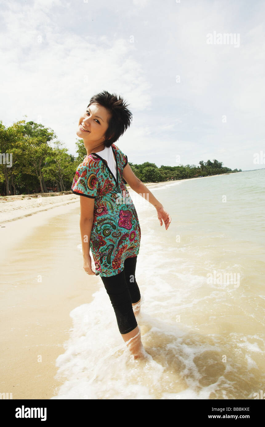 Woman walking on beach, looking over shoulder Stock Photo - Alamy