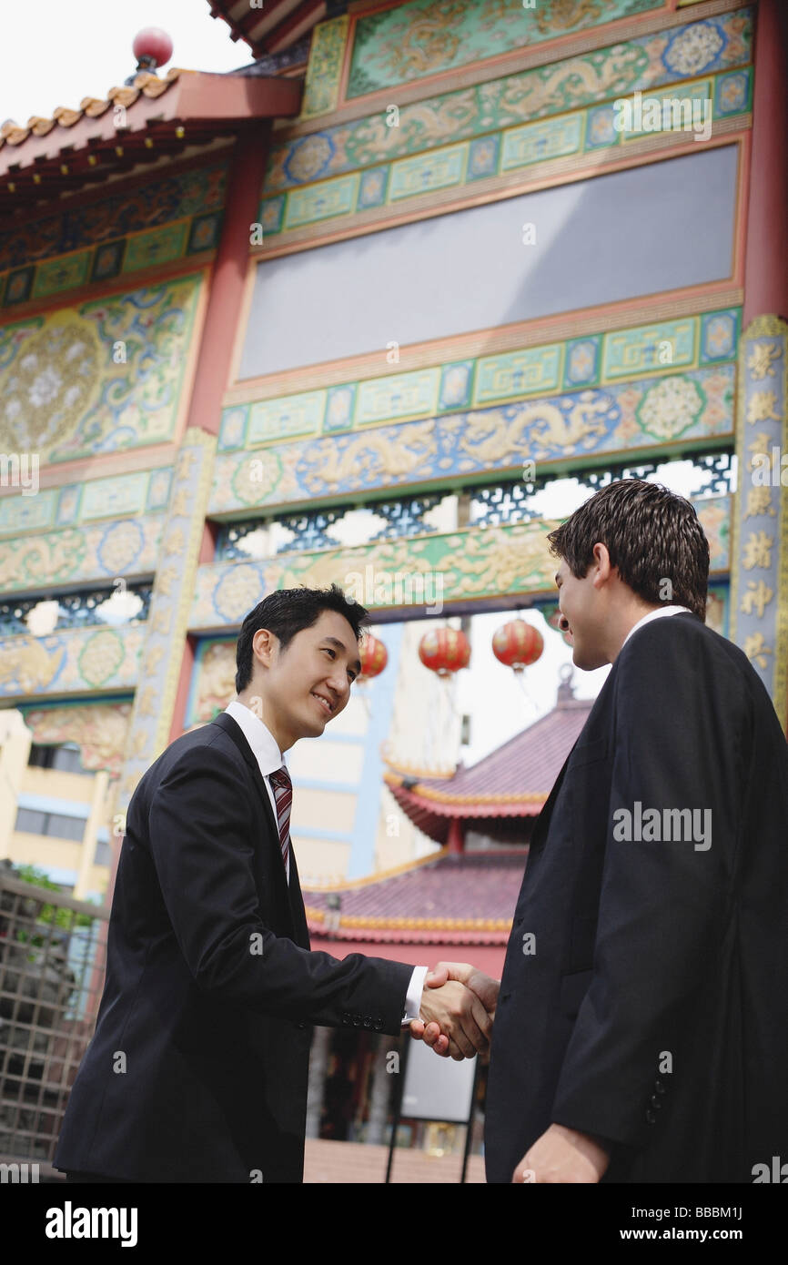 Businessmen shaking hands, temple gate in the background Stock Photo ...