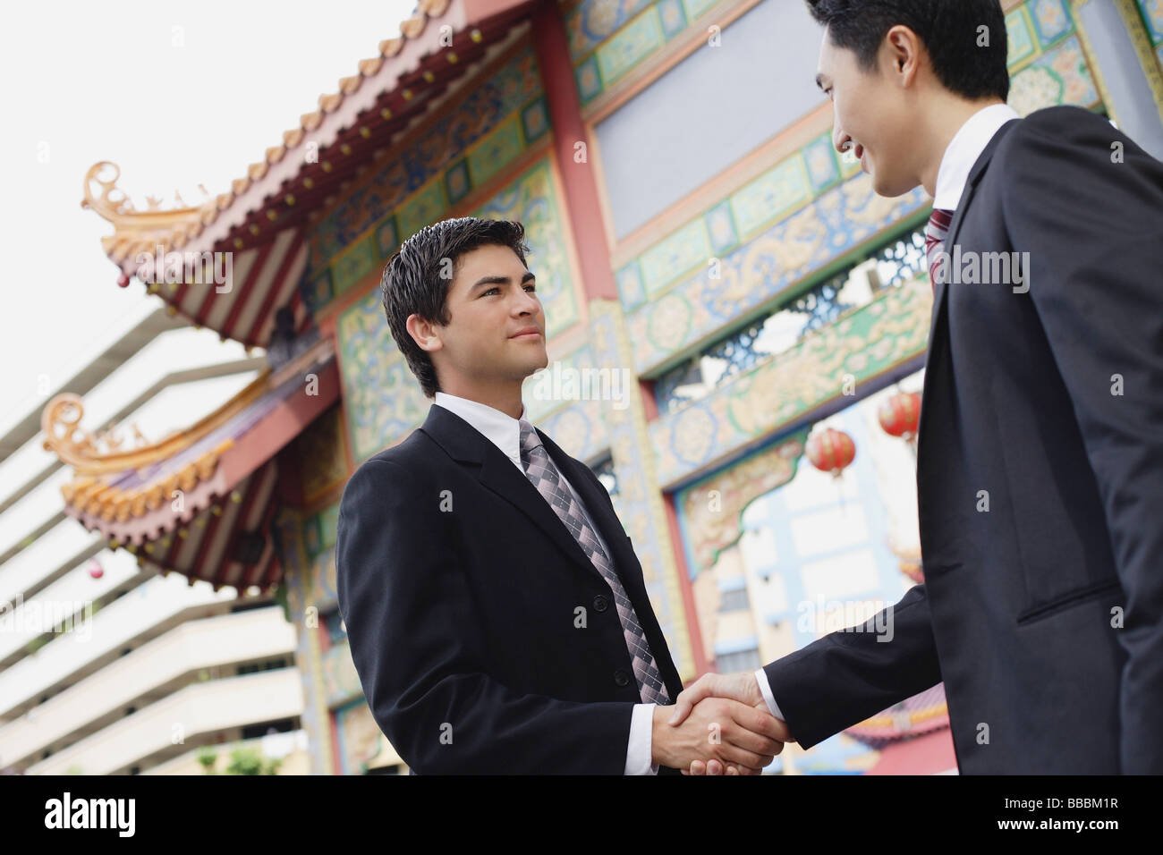 Two businessmen shaking hands, temple gate in the background Stock ...