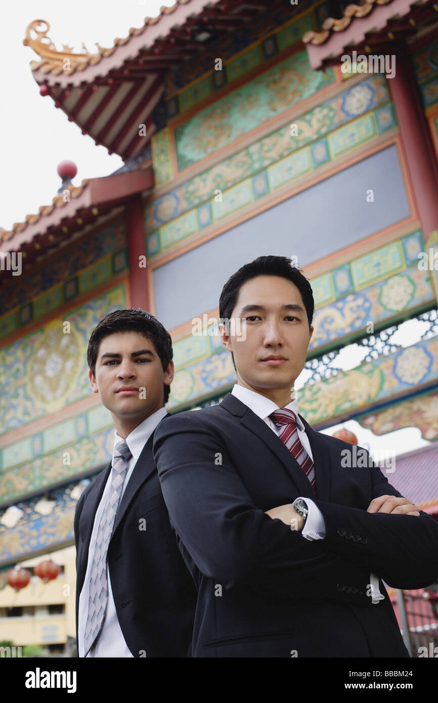 Two businessmen standing, looking at camera, temple gate in the ...
