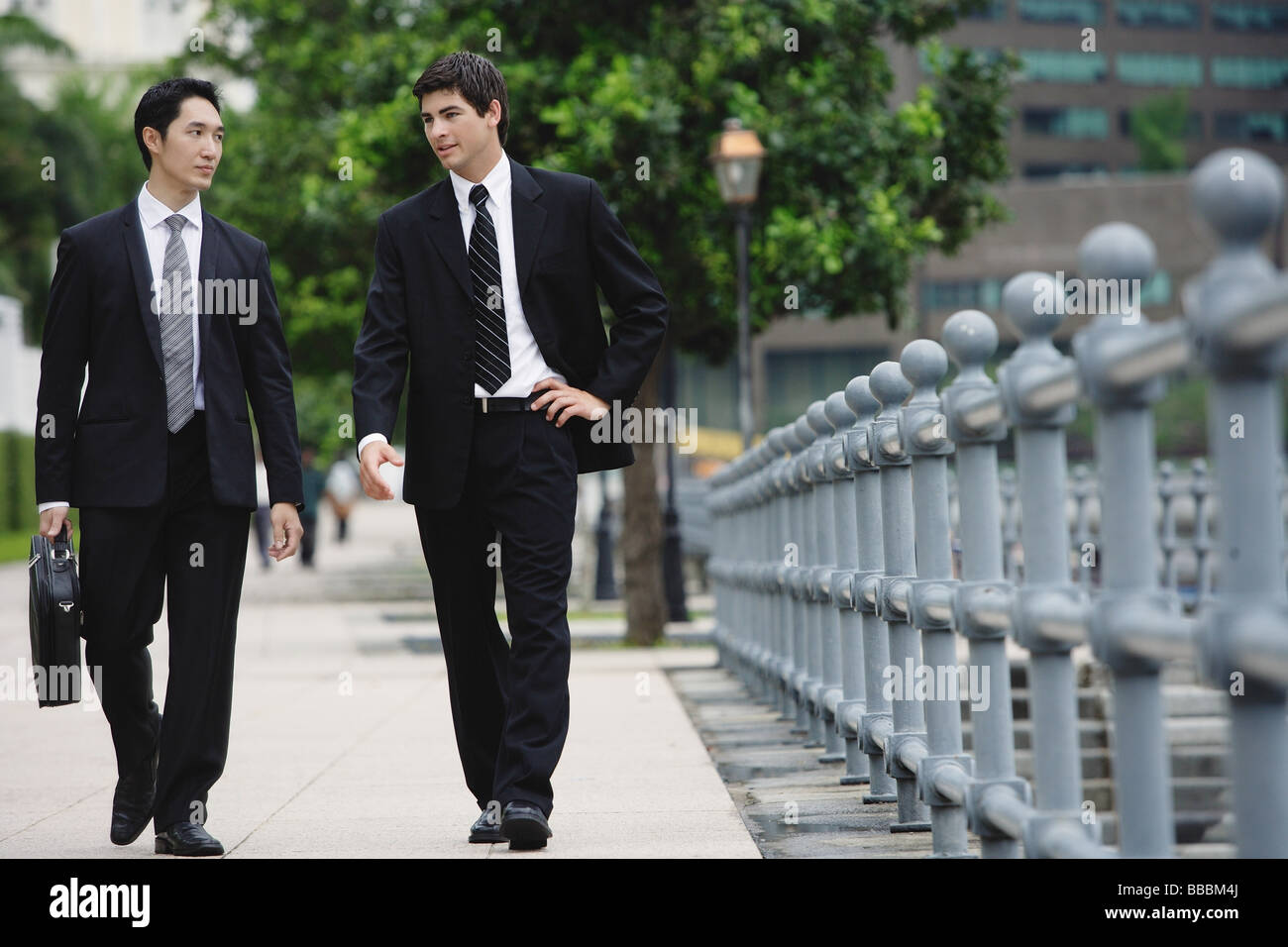 Two businessmen walking side by side, talking Stock Photo - Alamy