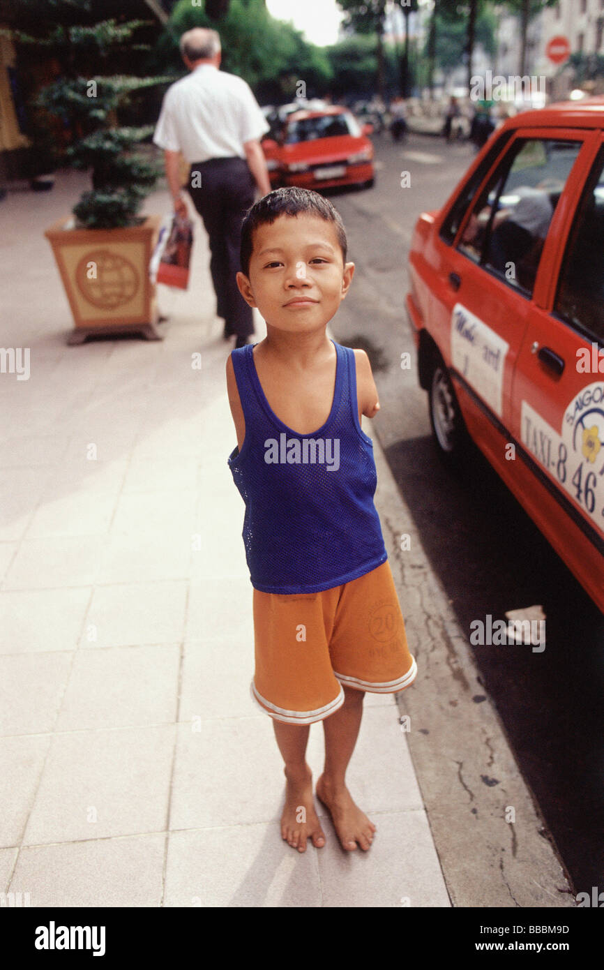 Vietnam, Ho Chi Minh City, A young boy without arms standing on a ...