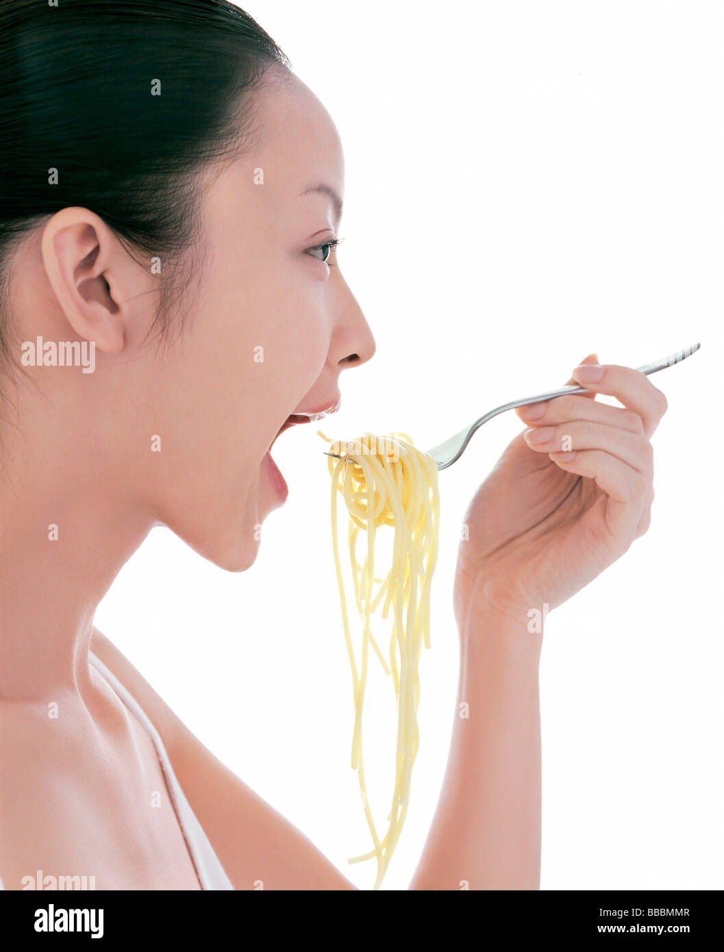 Young woman eating spaghetti, side view Stock Photo - Alamy