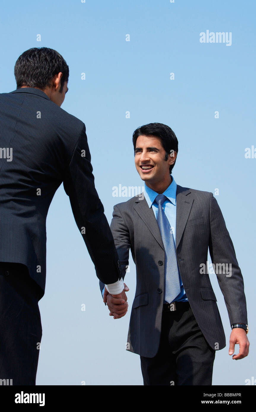 two businessmen shake hands (vertical Stock Photo - Alamy