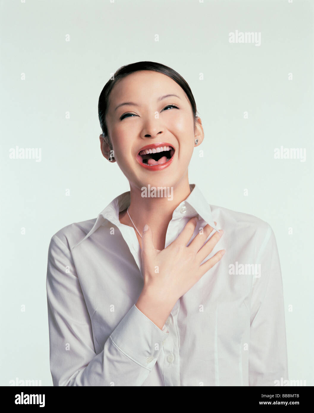 Young woman laughing, hand on chest Stock Photo - Alamy