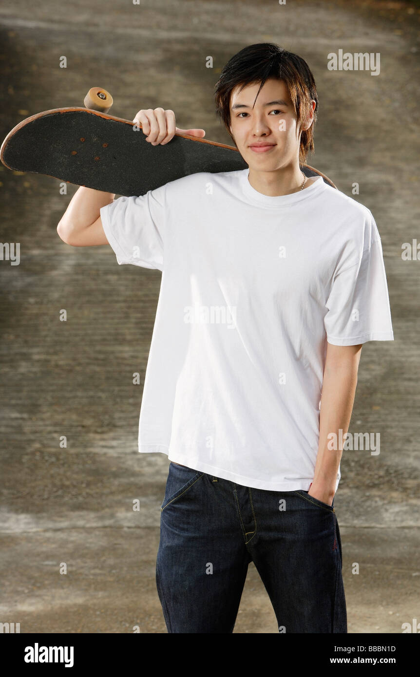 Young man holding skateboard over shoulder Stock Photo - Alamy