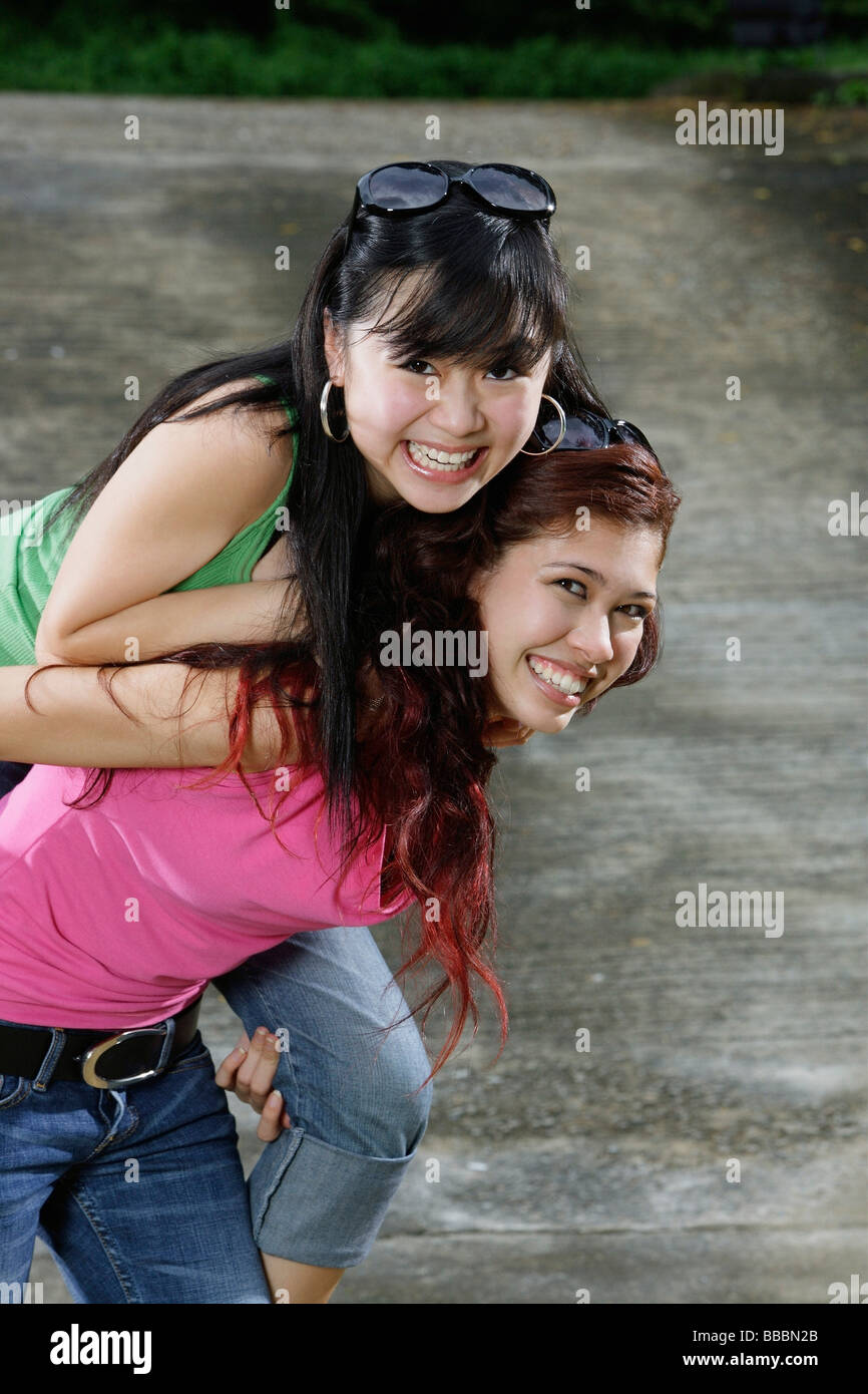 Teenage girl carrying another girl on her back Stock Photo - Alamy