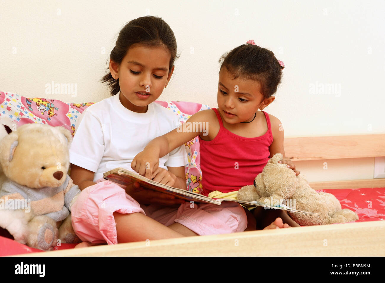 Sisters reading story book Stock Photo - Alamy