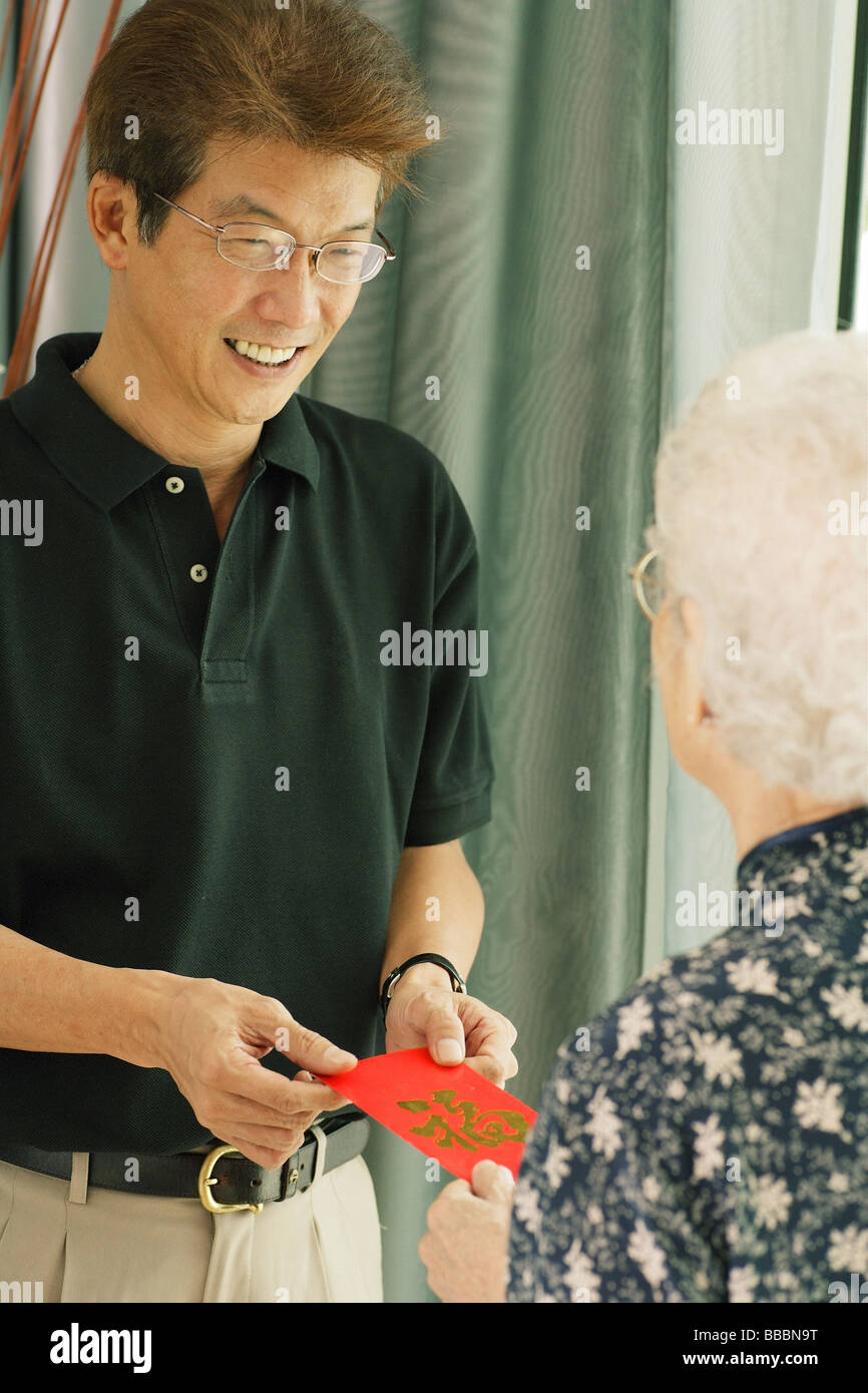 Mature man giving red packet to a senior woman Stock Photo - Alamy