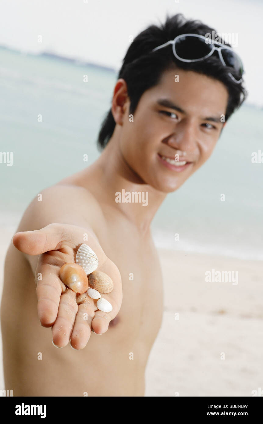 Man standing on beach, holding shells and stones in palm of hand Stock ...