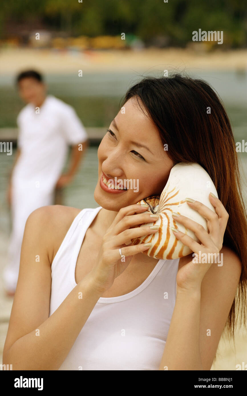 Woman holding seashell to ear hi-res stock photography and images - Alamy