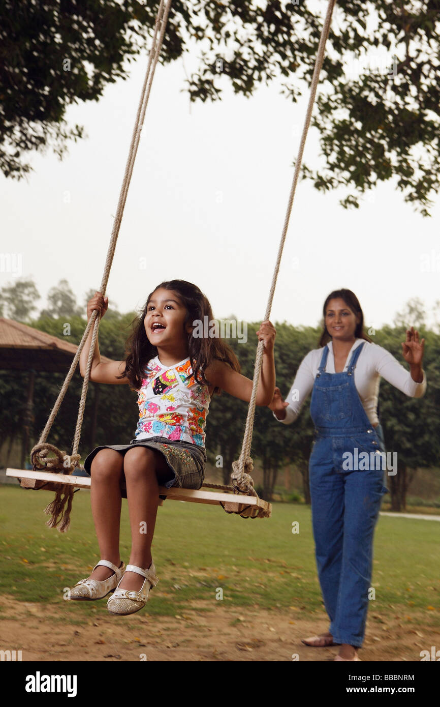 mom pushing daughter in swing Stock Photo - Alamy