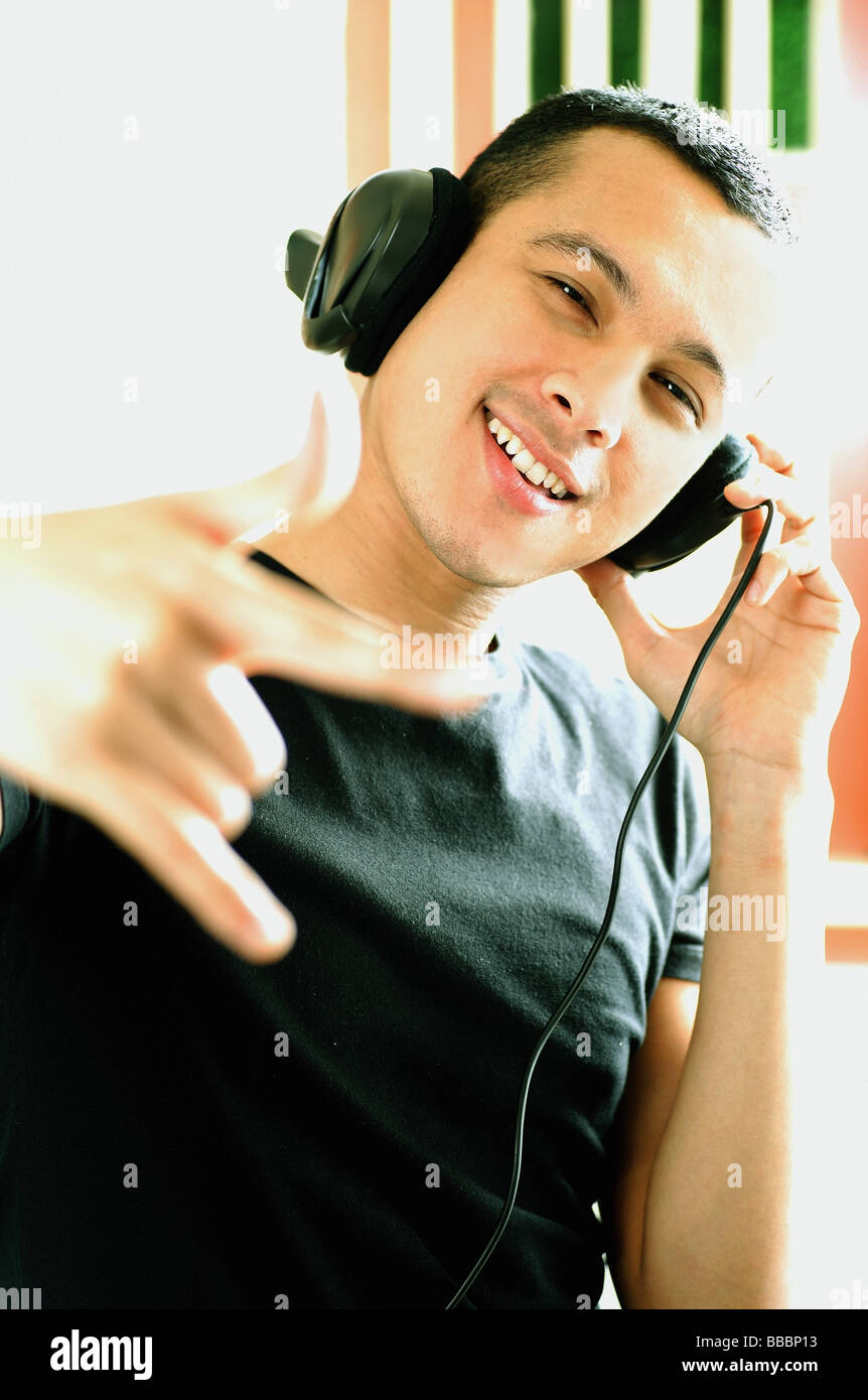 Young man with headphones, making hand sign Stock Photo - Alamy