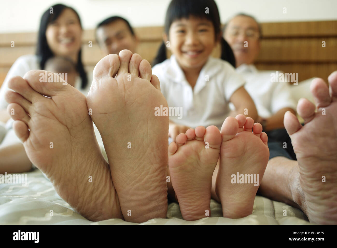 Three generation family on bed, focus on their feet Stock Photo - Alamy