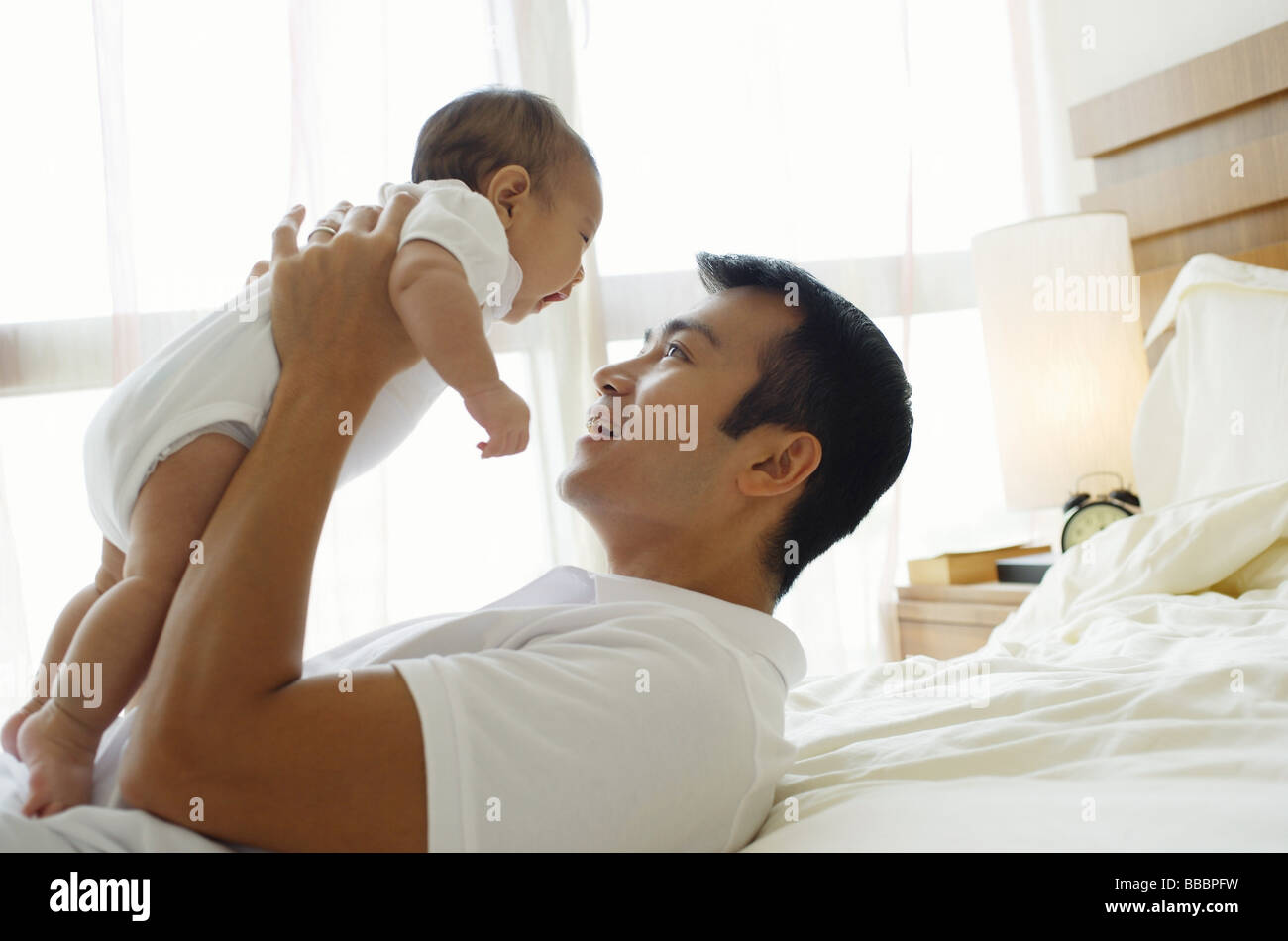 Father carrying baby daughter, lying on bed Stock Photo - Alamy