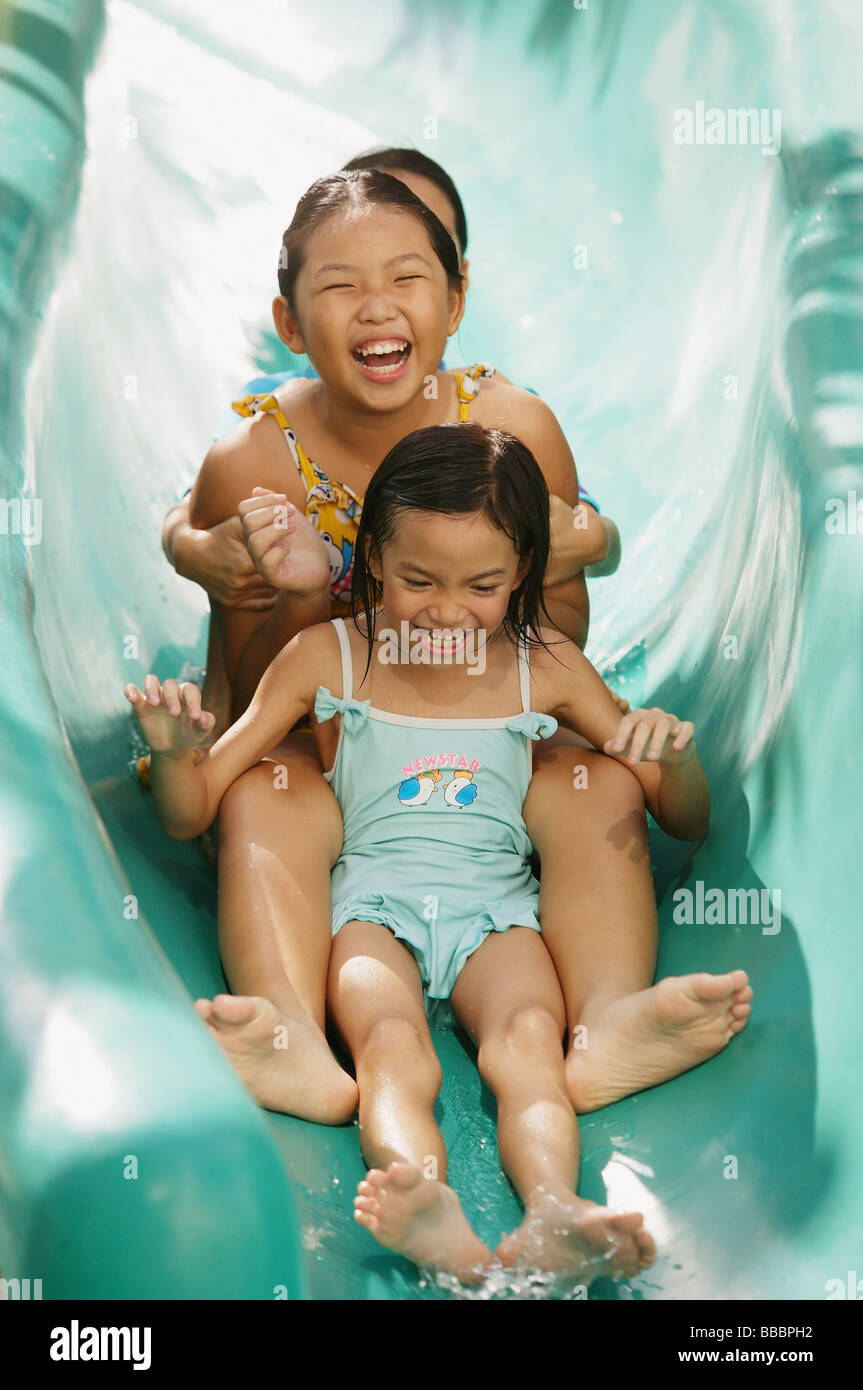 Three girls going down water slide Stock Photo - Alamy