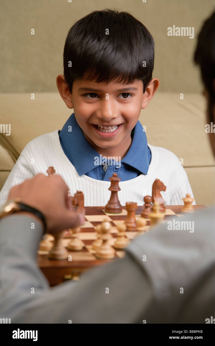 boy plays chess with father and smiles (vertical Stock Photo - Alamy