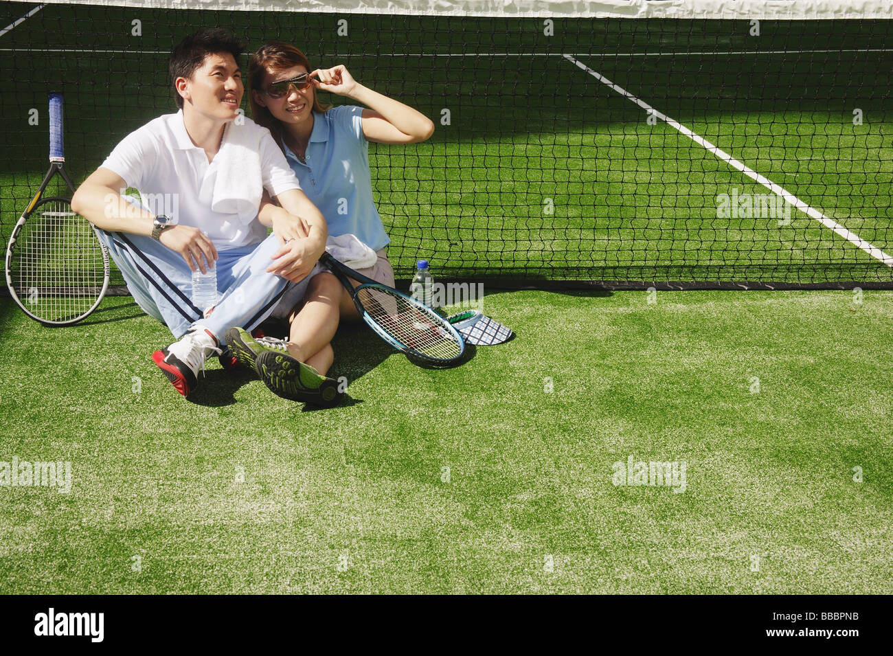 Couple sitting down on tennis court, side by side Stock Photo - Alamy