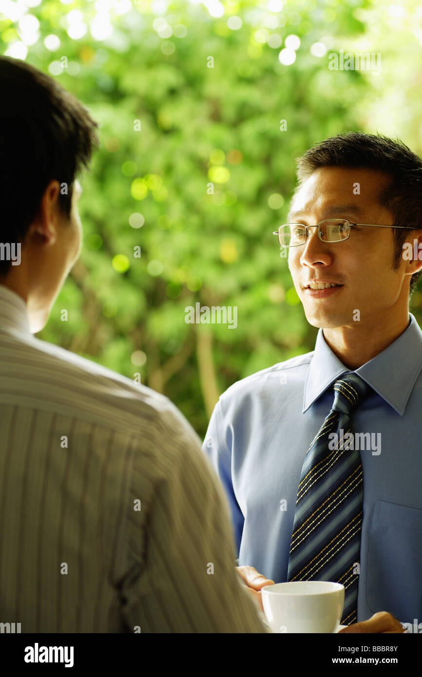 Two businessmen standing face to face, talking Stock Photo - Alamy