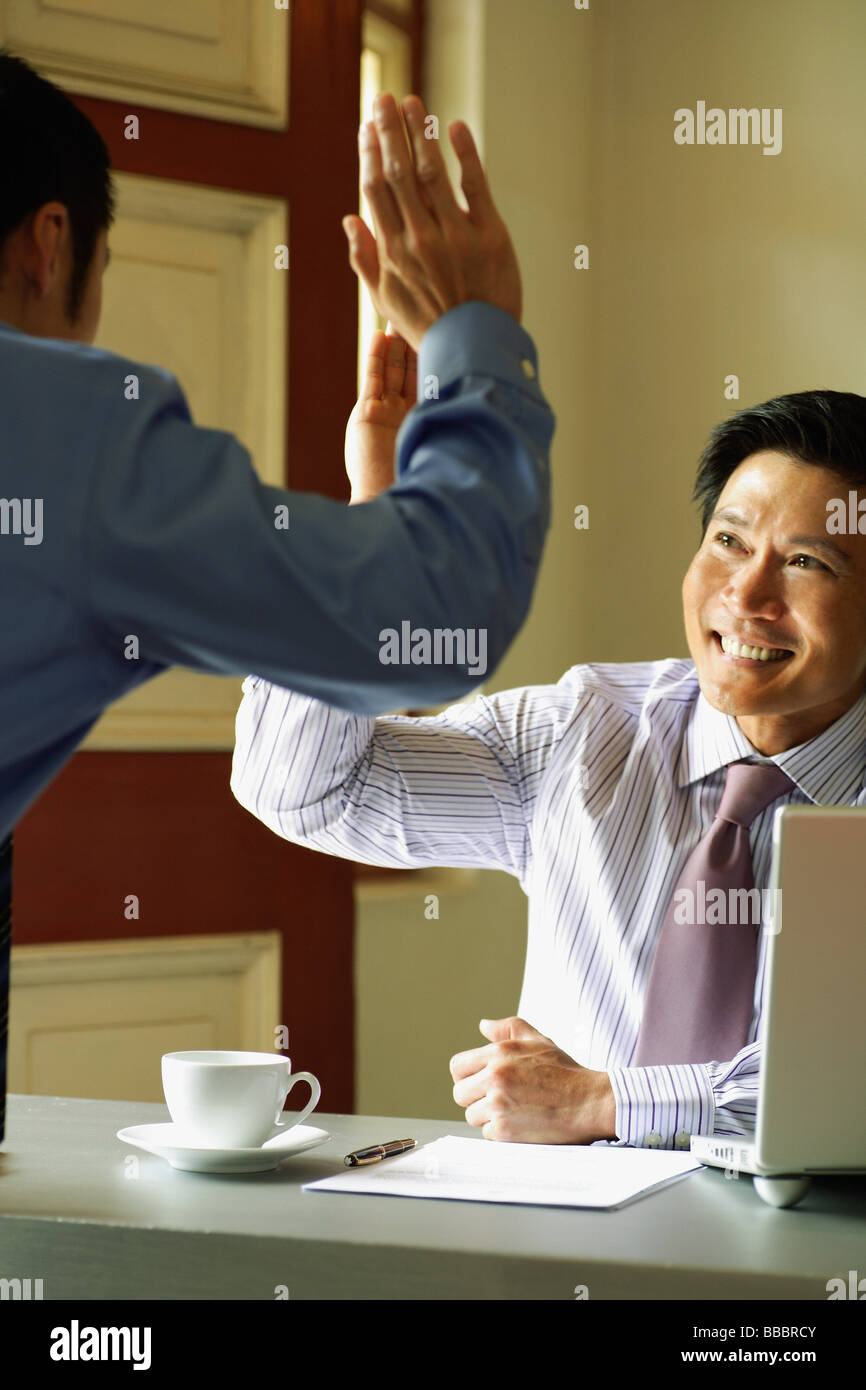 Businessmen giving high five over desk Stock Photo - Alamy