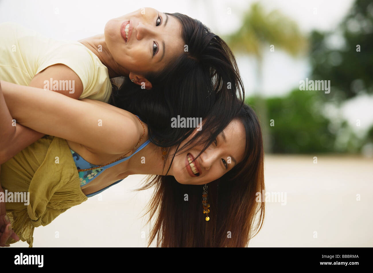Young woman carrying friend on back, looking at camera Stock Photo - Alamy