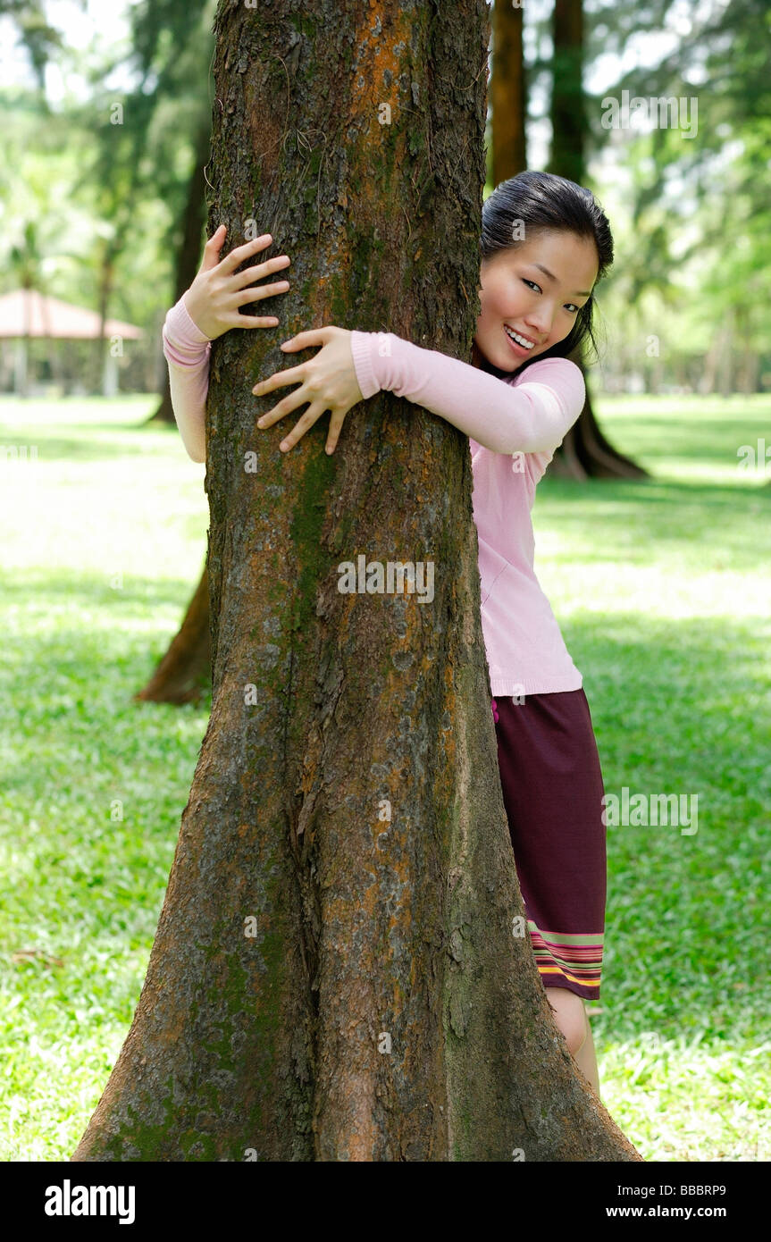Young woman with arms around a tree Stock Photo - Alamy