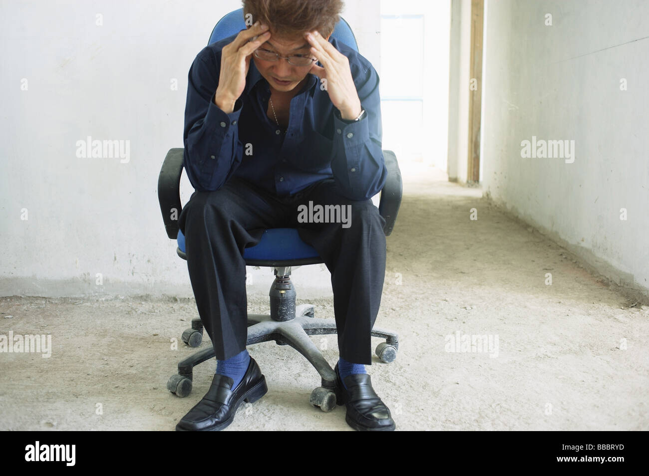 Man sitting in empty room, hand on head Stock Photo - Alamy