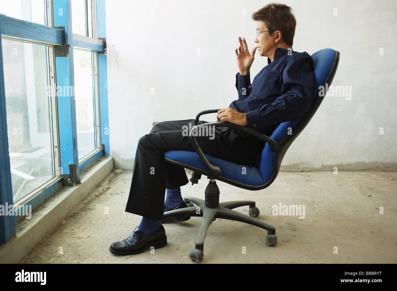Man sitting in empty room, looking out of window Stock Photo - Alamy