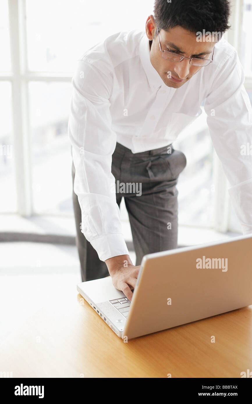Man using laptop, bending over table Stock Photo - Alamy