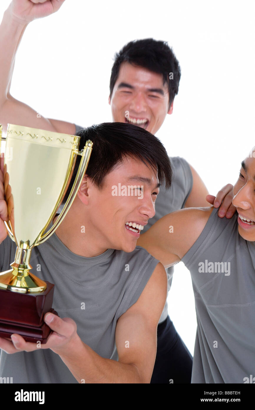 Three people celebrating with trophy Stock Photo - Alamy