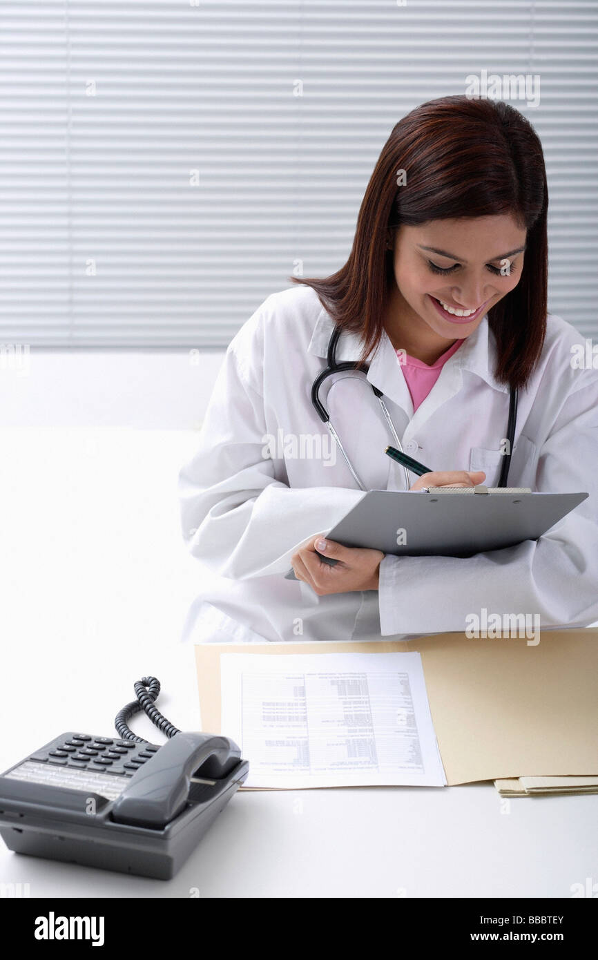Doctor smiling while writing report Stock Photo - Alamy
