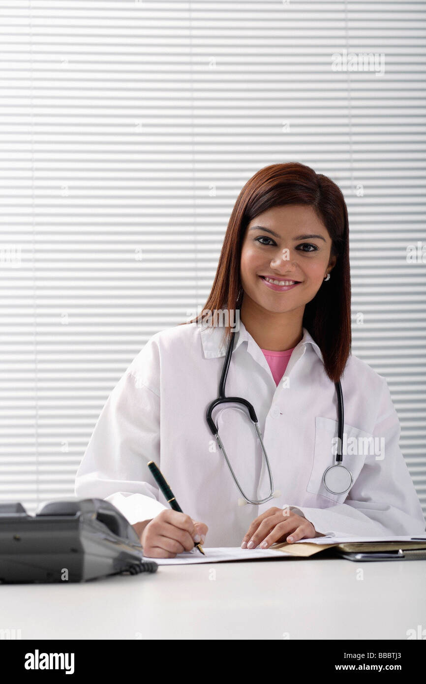 Smiling doctor working with report Stock Photo - Alamy